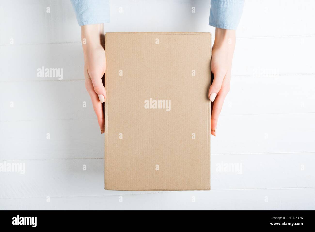 Rectangular cardboard box in female hands. Top view, white background ...