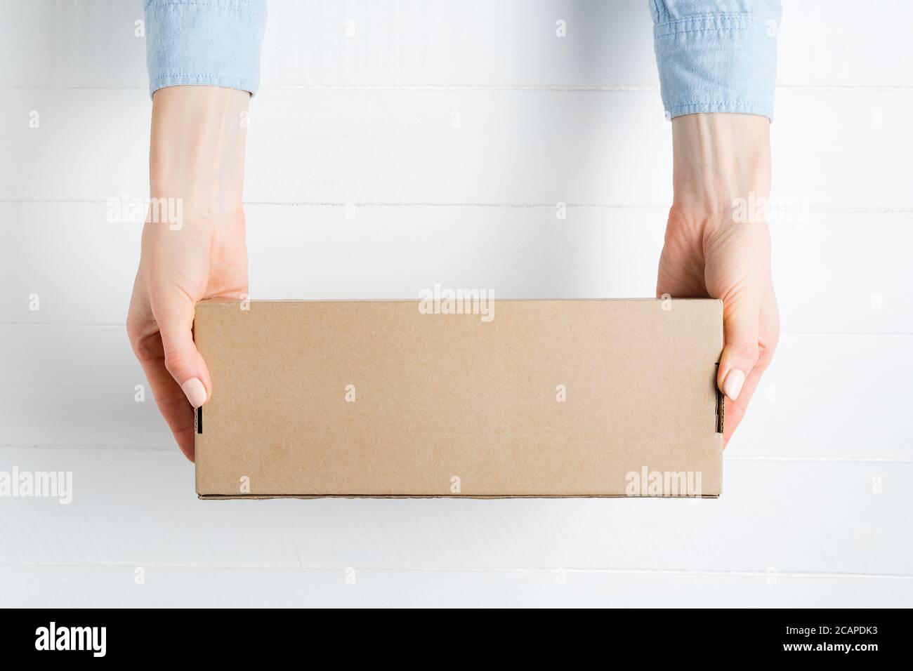 Rectangular cardboard box in female hands. Top view, white background ...