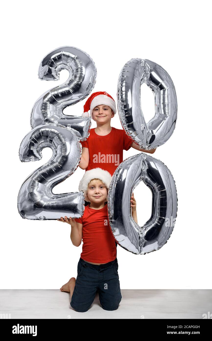 Two boys in Christmas hats are holding silver inflatable figure 2020 ...