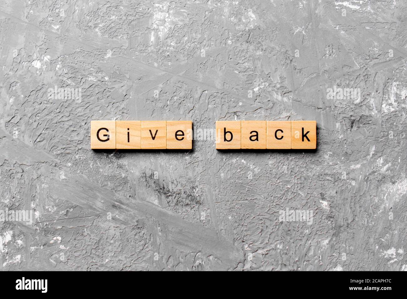 Give Back word written on wood block. Give Back text on table, concept ...