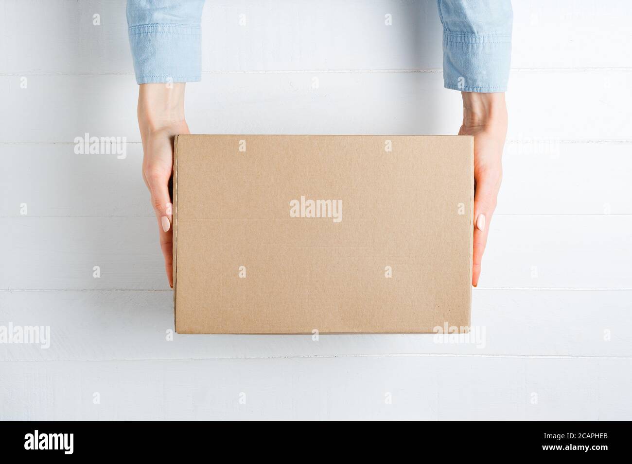 Rectangular cardboard box in female hands. Top view, white background ...