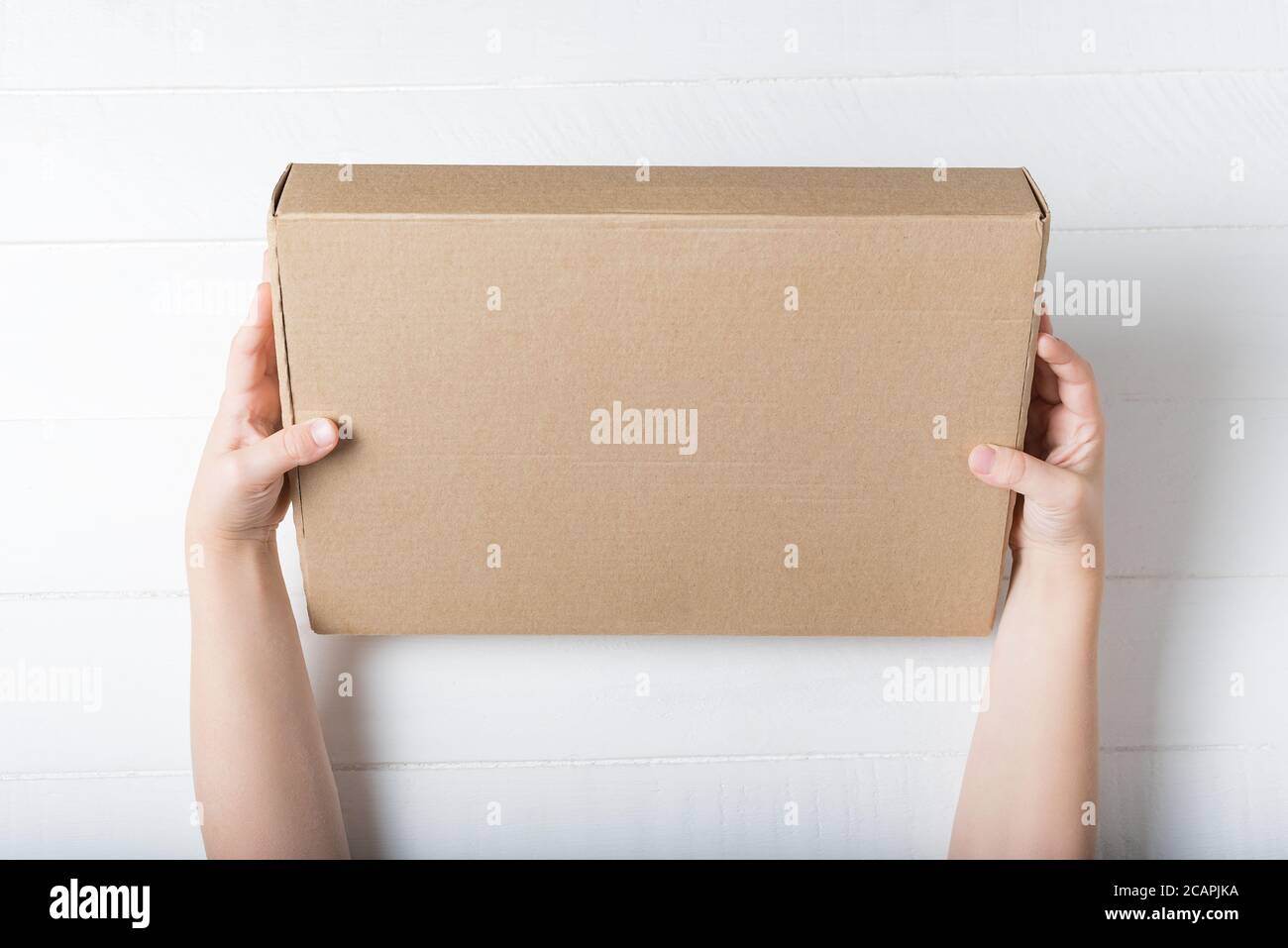 Rectangular cardboard box in children's hands. Top view, white ...
