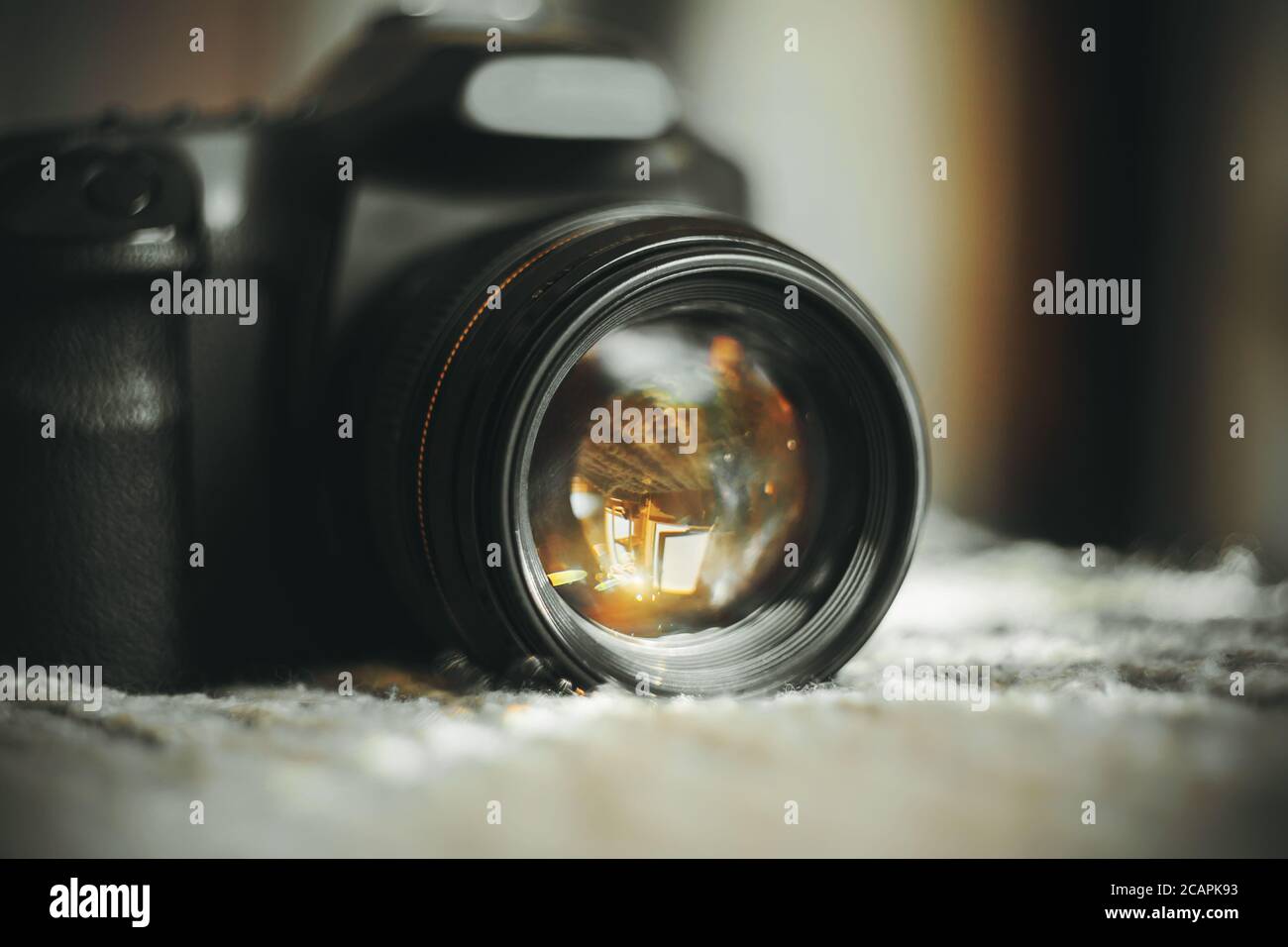 On a gray woolen cloth is a new SLR camera with a lens that reflects ...