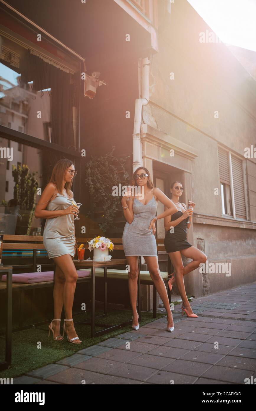 Three attractive caucasian women in short tight dresses are drinking ...