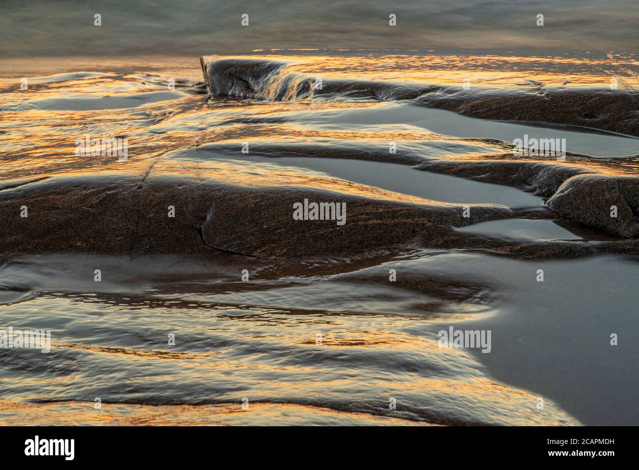 Wave -polished granite along Lake Superior shore at sunset, Neys ...