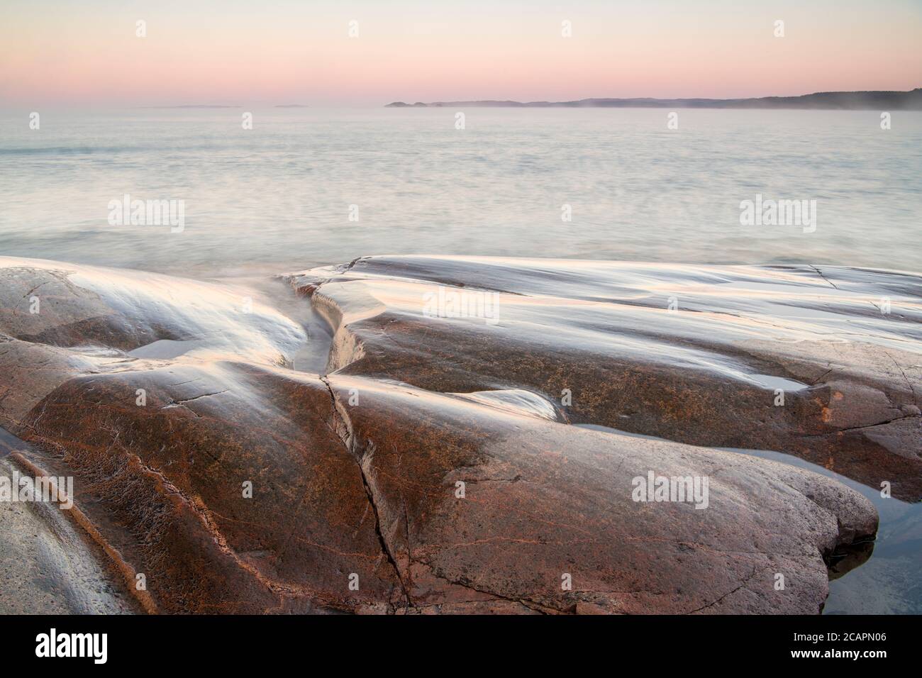 Wave polished rock outcrop at the shore of Lake Superior before dawn ...
