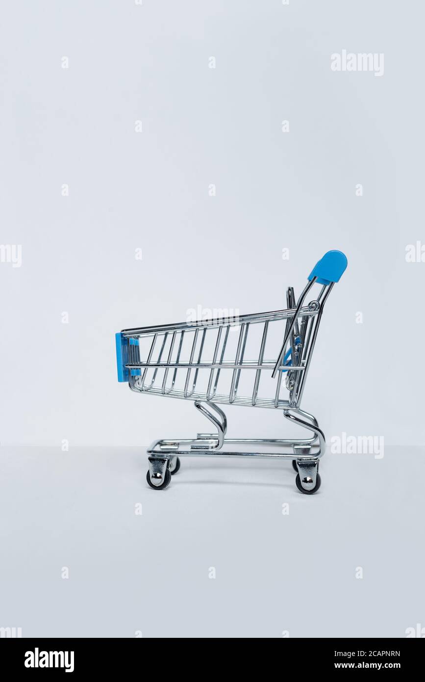 Small metal shopping trolley on a light background. Vertical frame ...