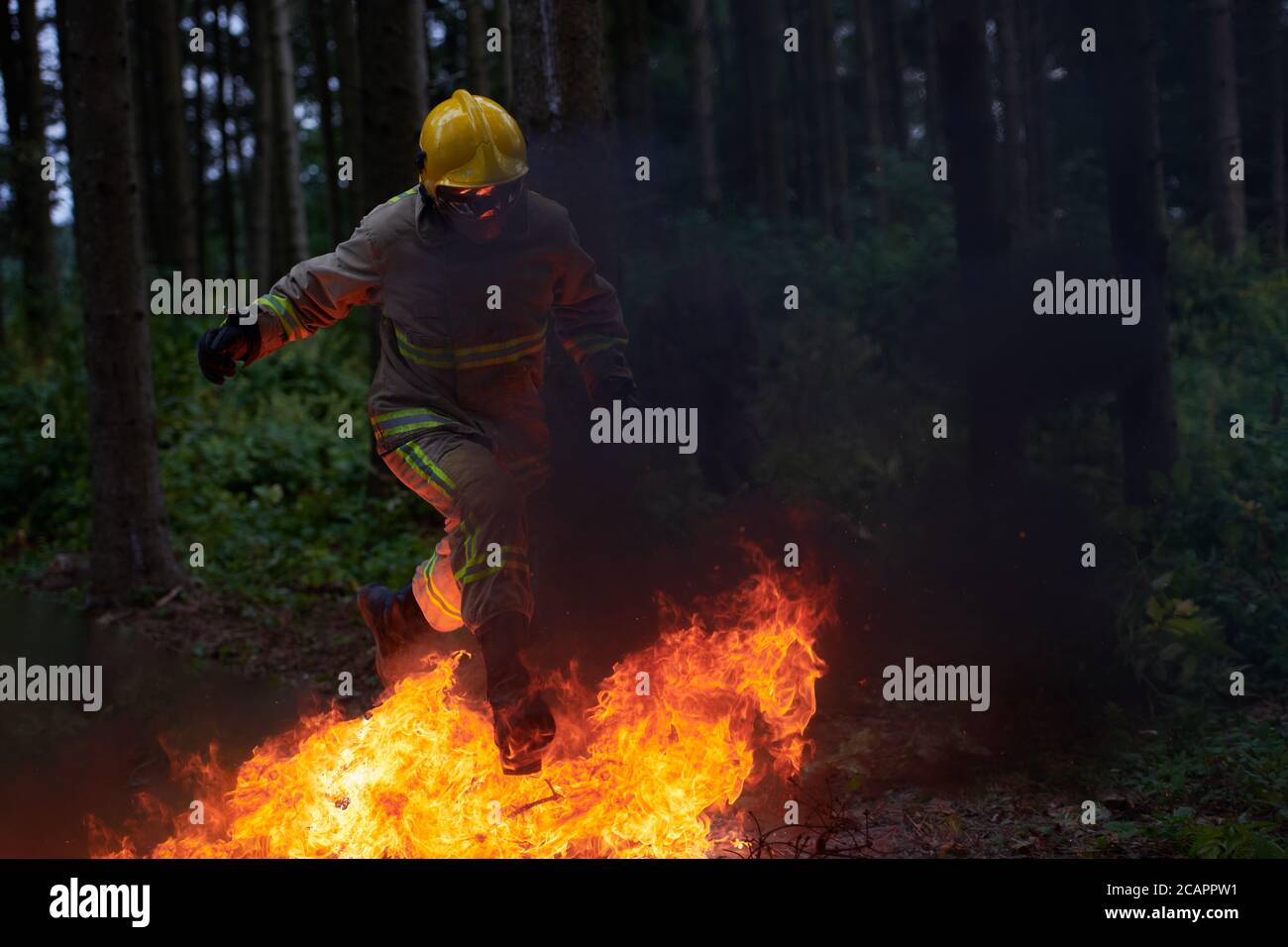 firefighter hero in action danger jumping over fire flame to rescue and ...