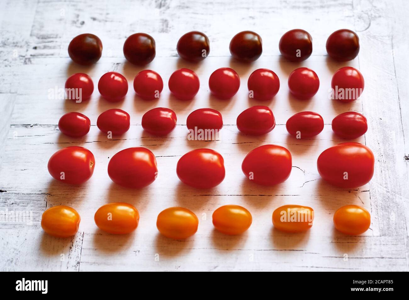 five types of cherry tomatoes on a light wooden background from above ...