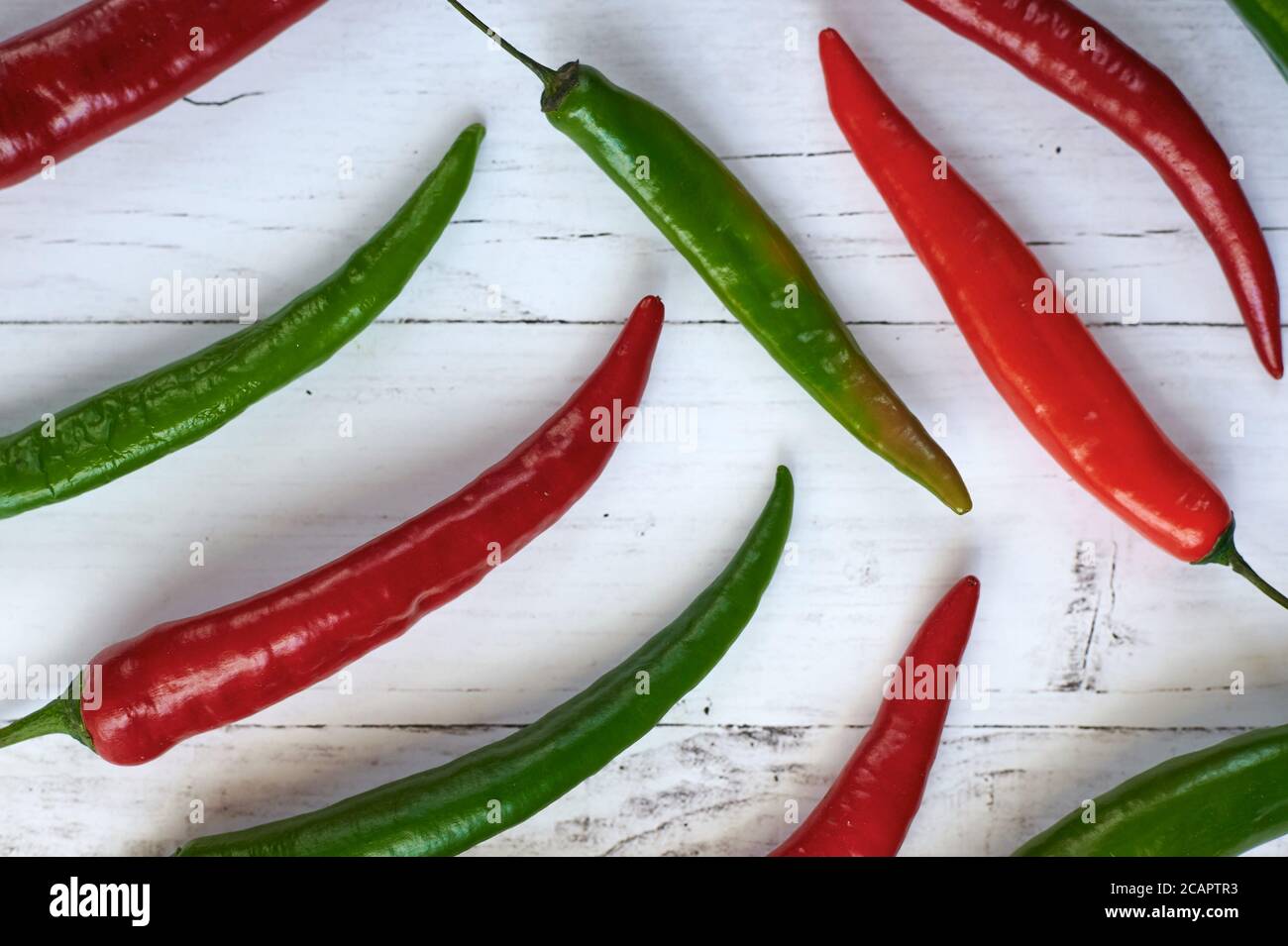spicy green and red chilli on a light background from above close up ...