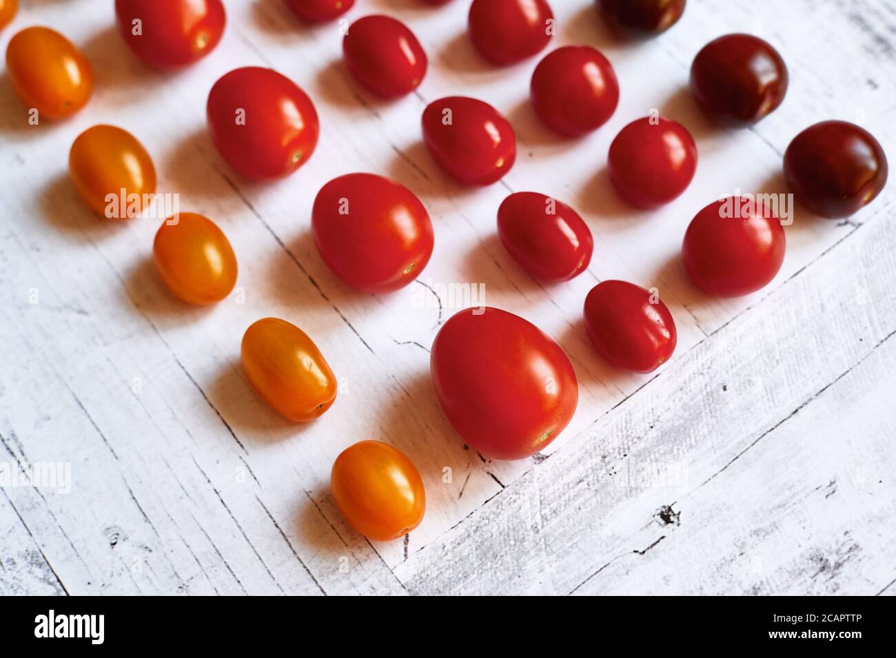 five types of cherry tomatoes on a light wooden background from above ...