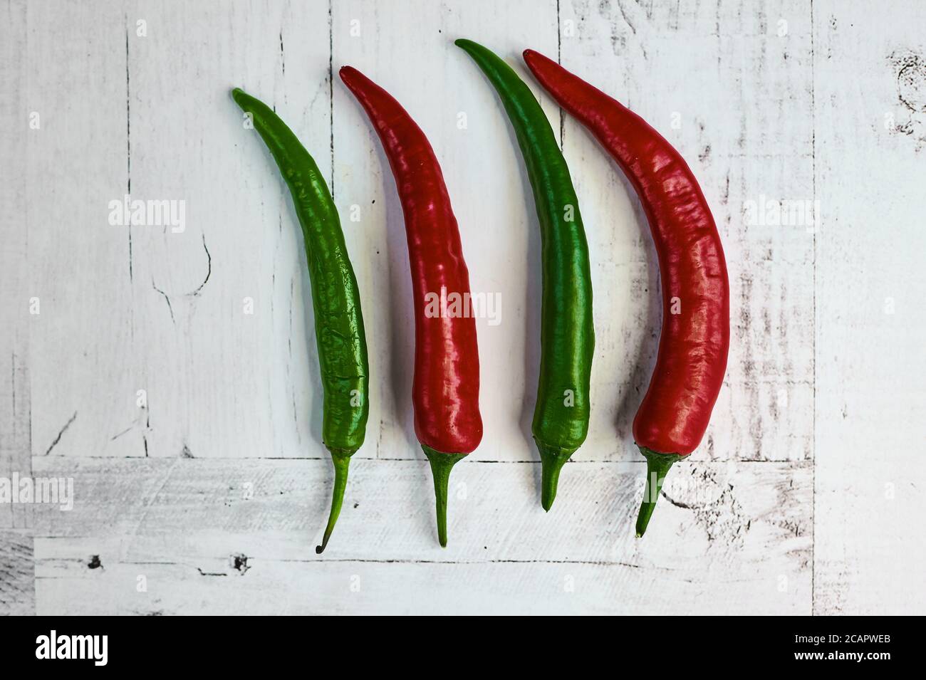 spicy green and red chilli on a light background from above close up ...