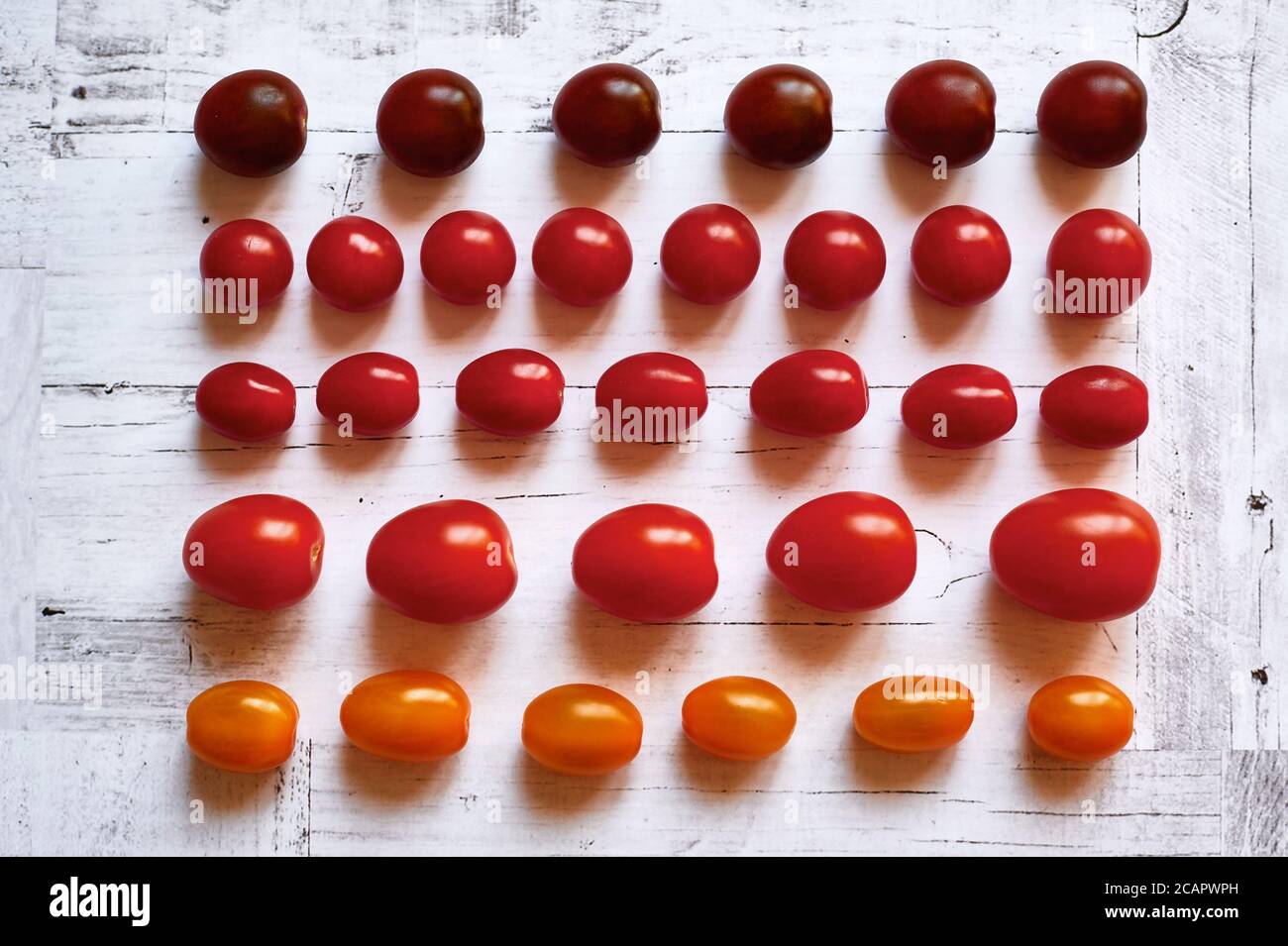 five types of cherry tomatoes on a light wooden background from above ...