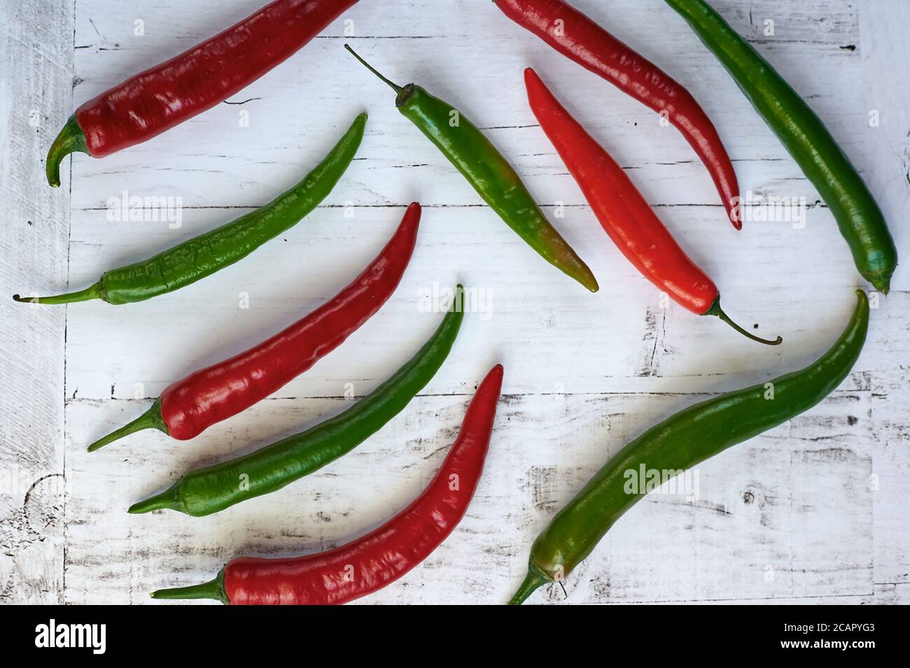 spicy green and red chilli on a light background from above close up ...
