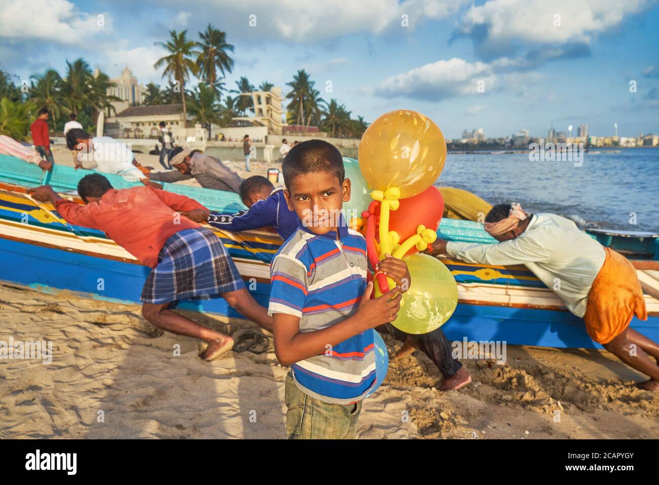 A boy selling colorful balloons at Chowpatty Beach, Mumbai, India ...