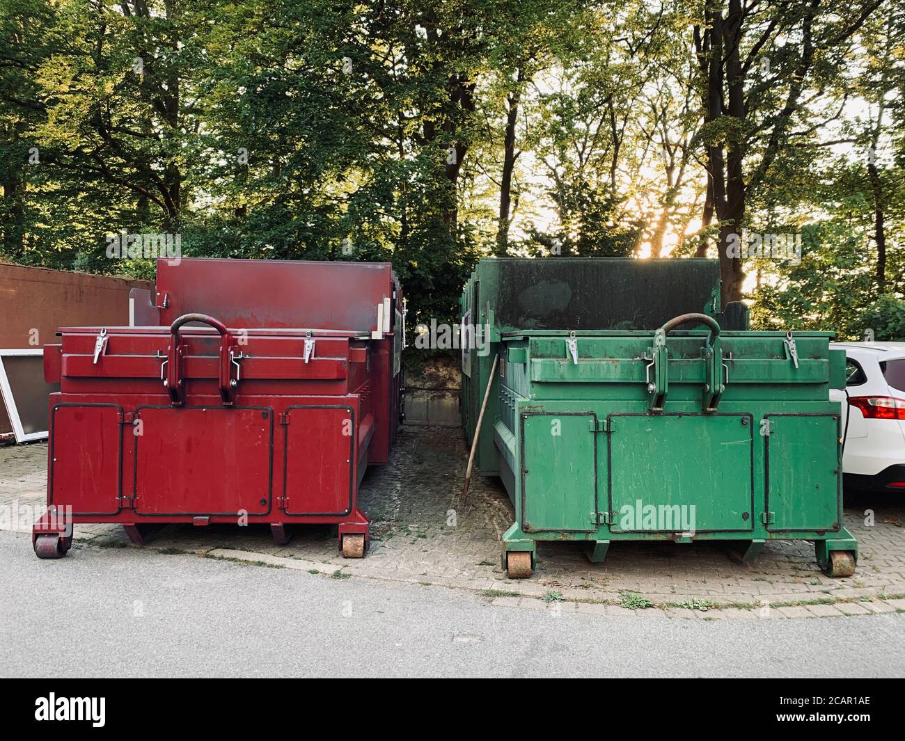 on an industrial site a green waste compactor and a red waste compactor ...