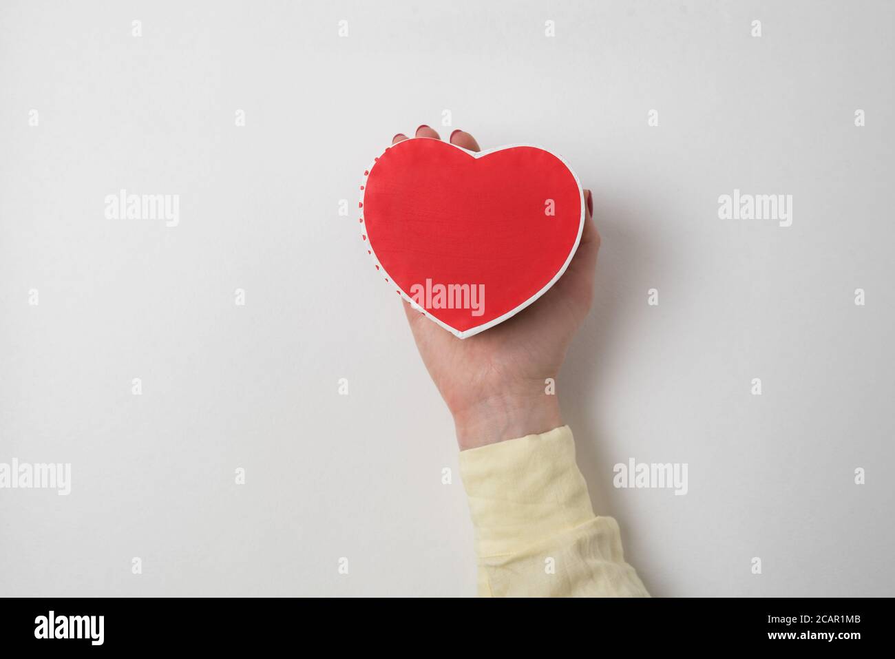 Small red heart shaped box on female palm isolated on white background ...