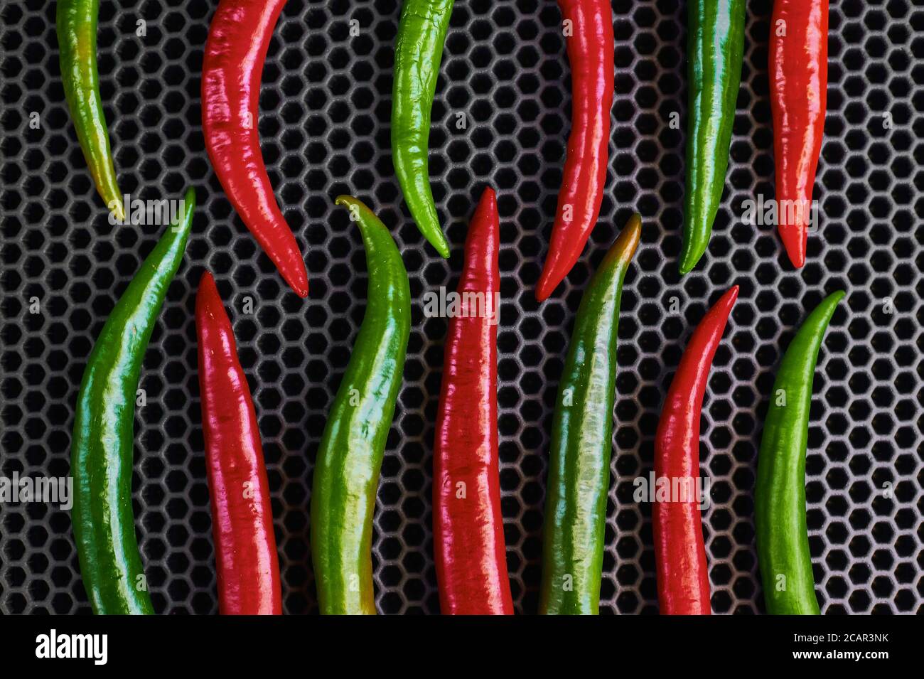 red and green hot chili pepper close-up against a dark background ...