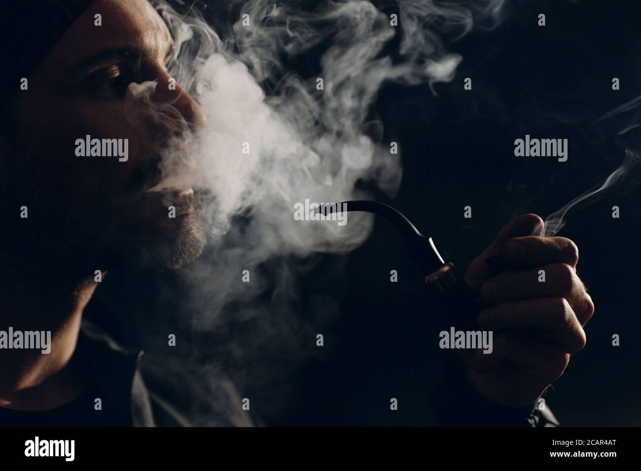 Man smoking a pipe on dark background. Back lit profile portrait Stock ...