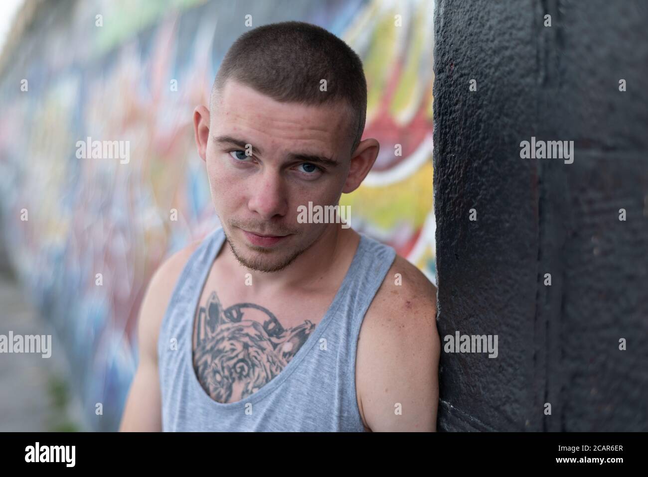 A bully guy in a sports shirt near a wall with graffiti Stock Photo - Alamy