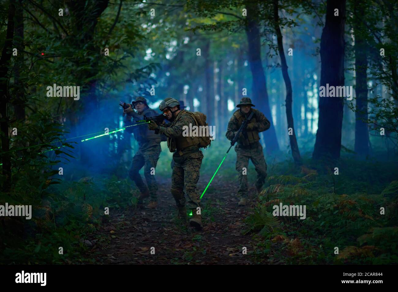 soldiers squad in action on night mission using laser sight beam lights ...
