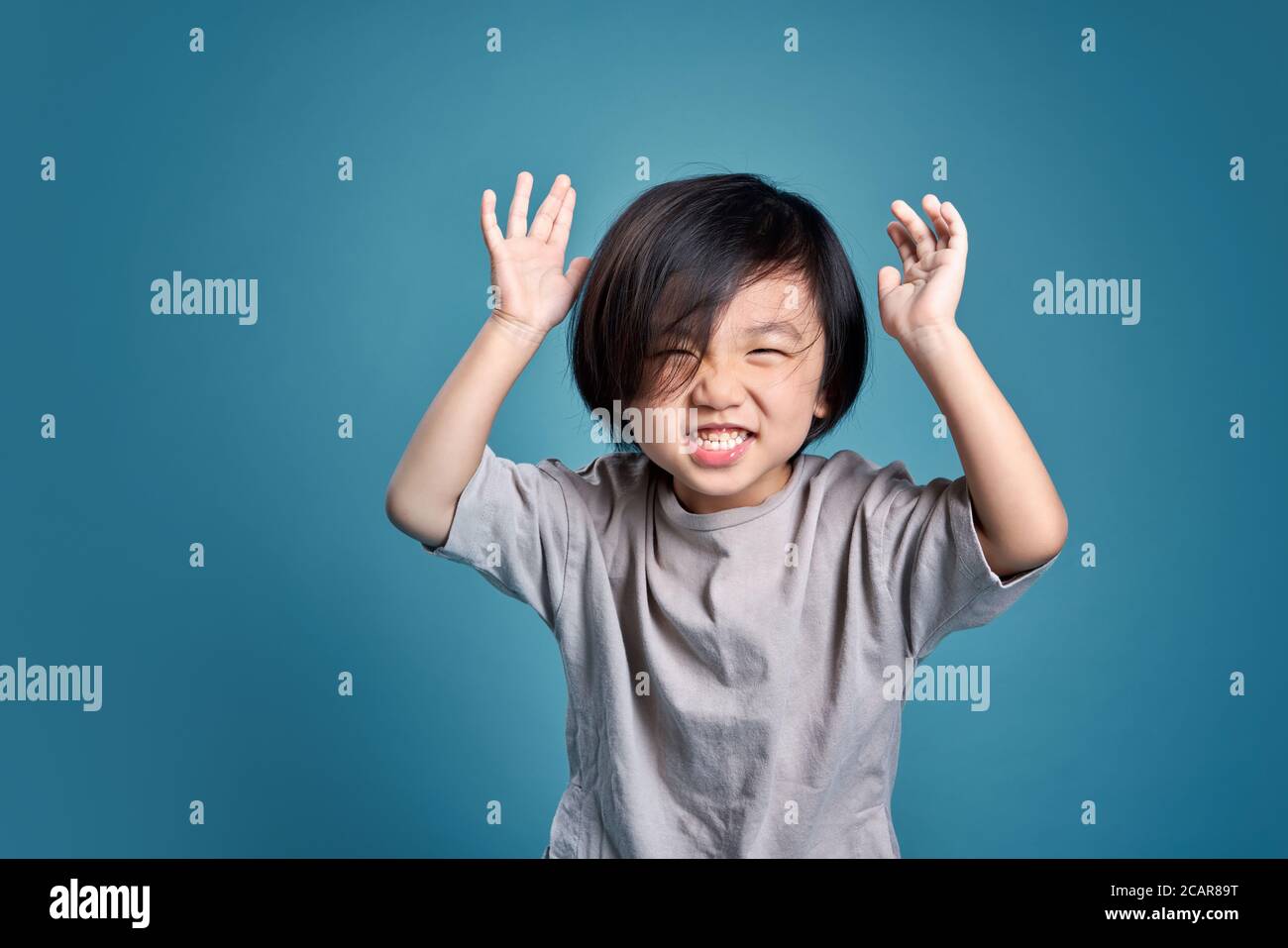Beautiful asian little kid rising both hand. Empty space in studio shot ...