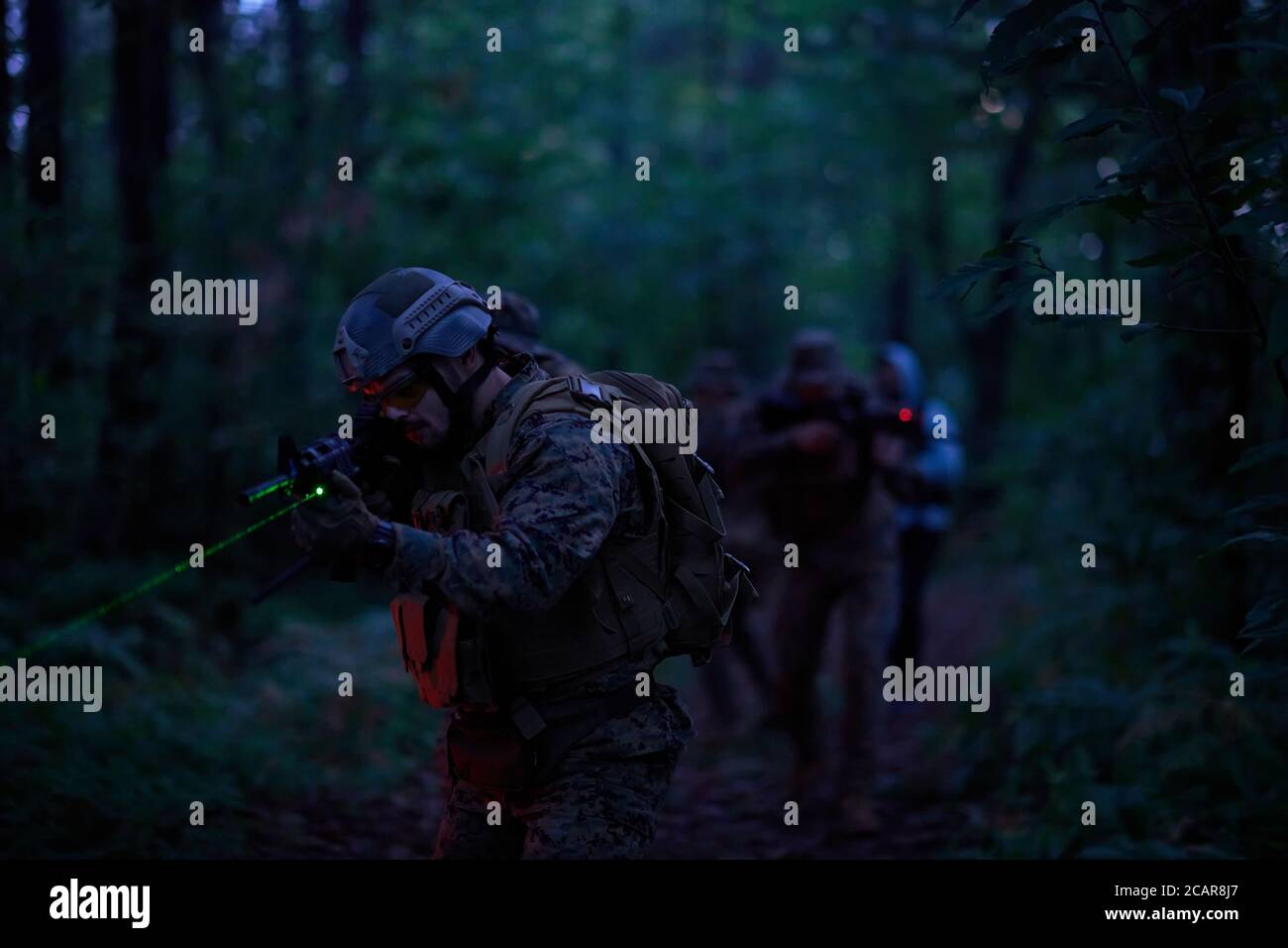 soldiers squad in action on night mission using laser sight beam lights ...