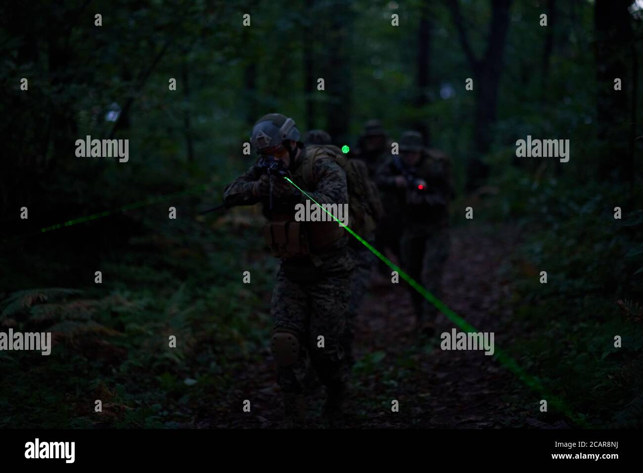 soldiers squad in action on night mission using laser sight beam lights ...