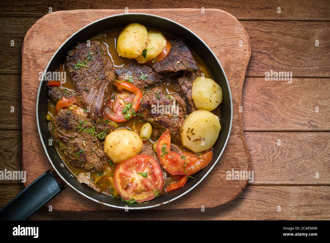 Homemade lunch. Pieces of meat in the iron pan. Isolated on wooden ...