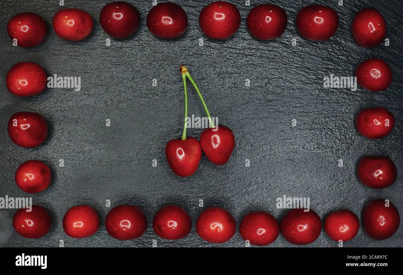 a frame of cherries on a black background and a sprig of cherries ...