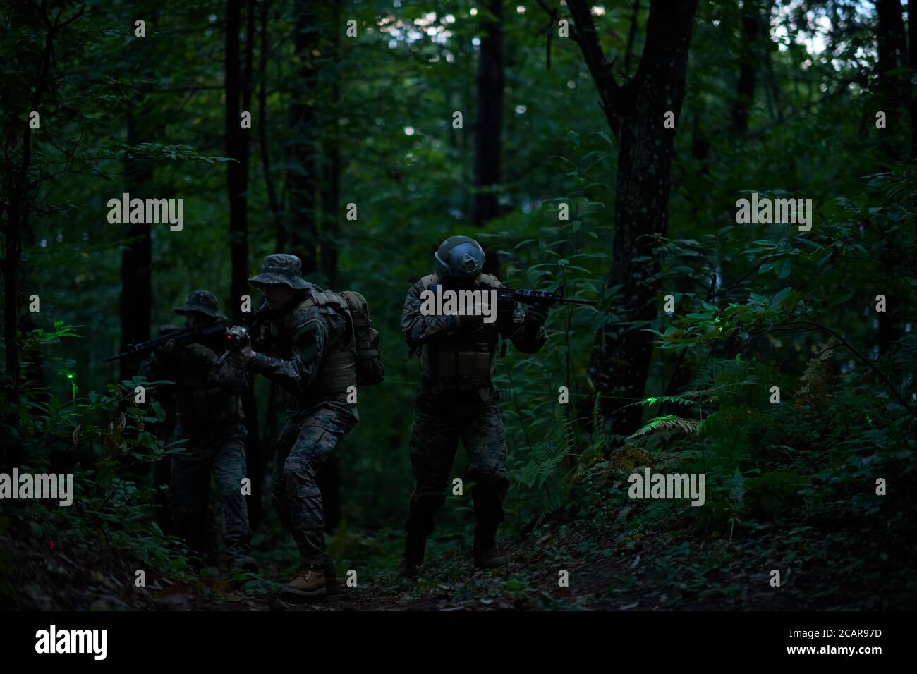 soldiers squad in action on night mission using laser sight beam lights ...