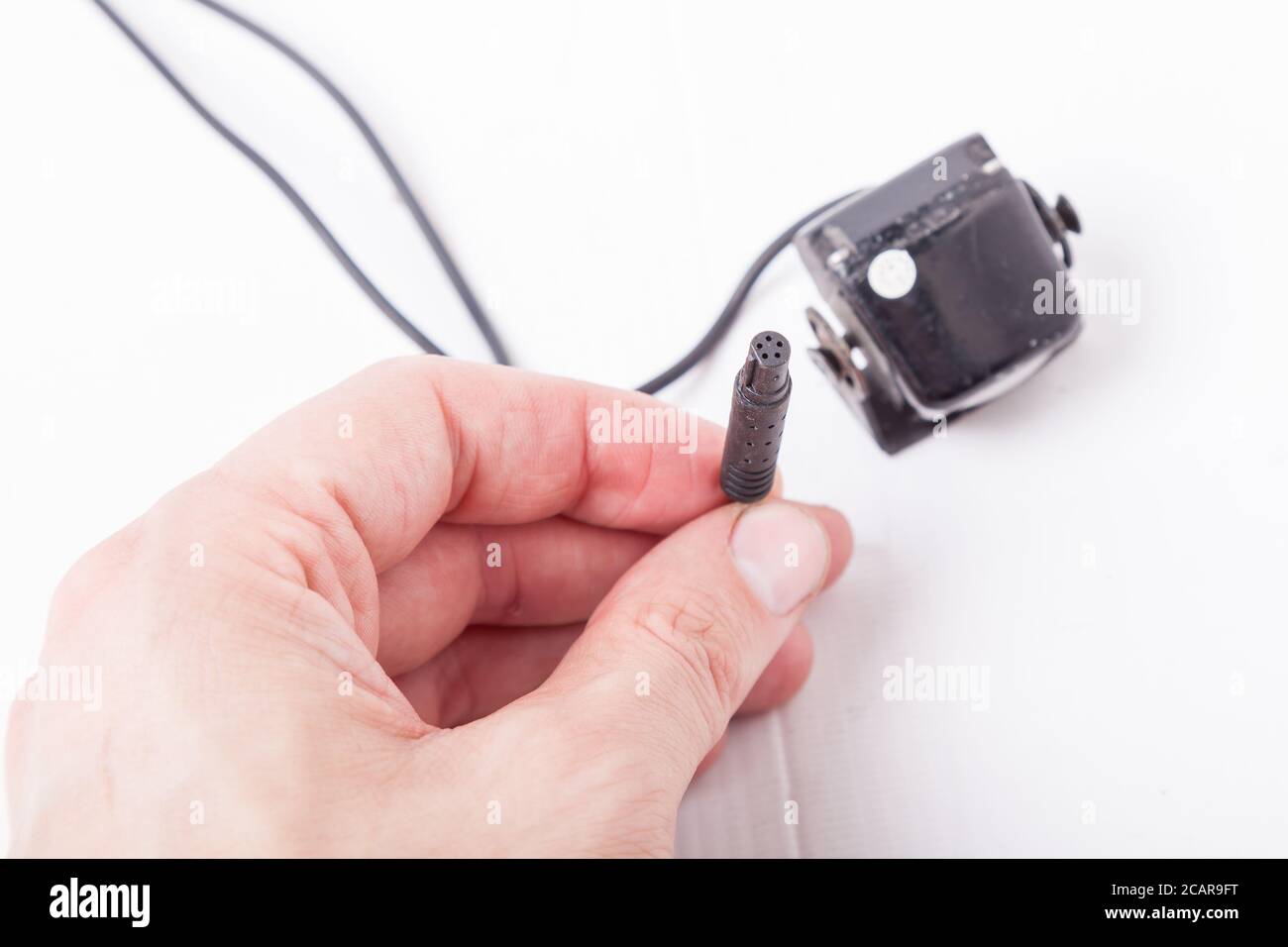 A close-up of the hand of a Caucasian man holding a black connector ...