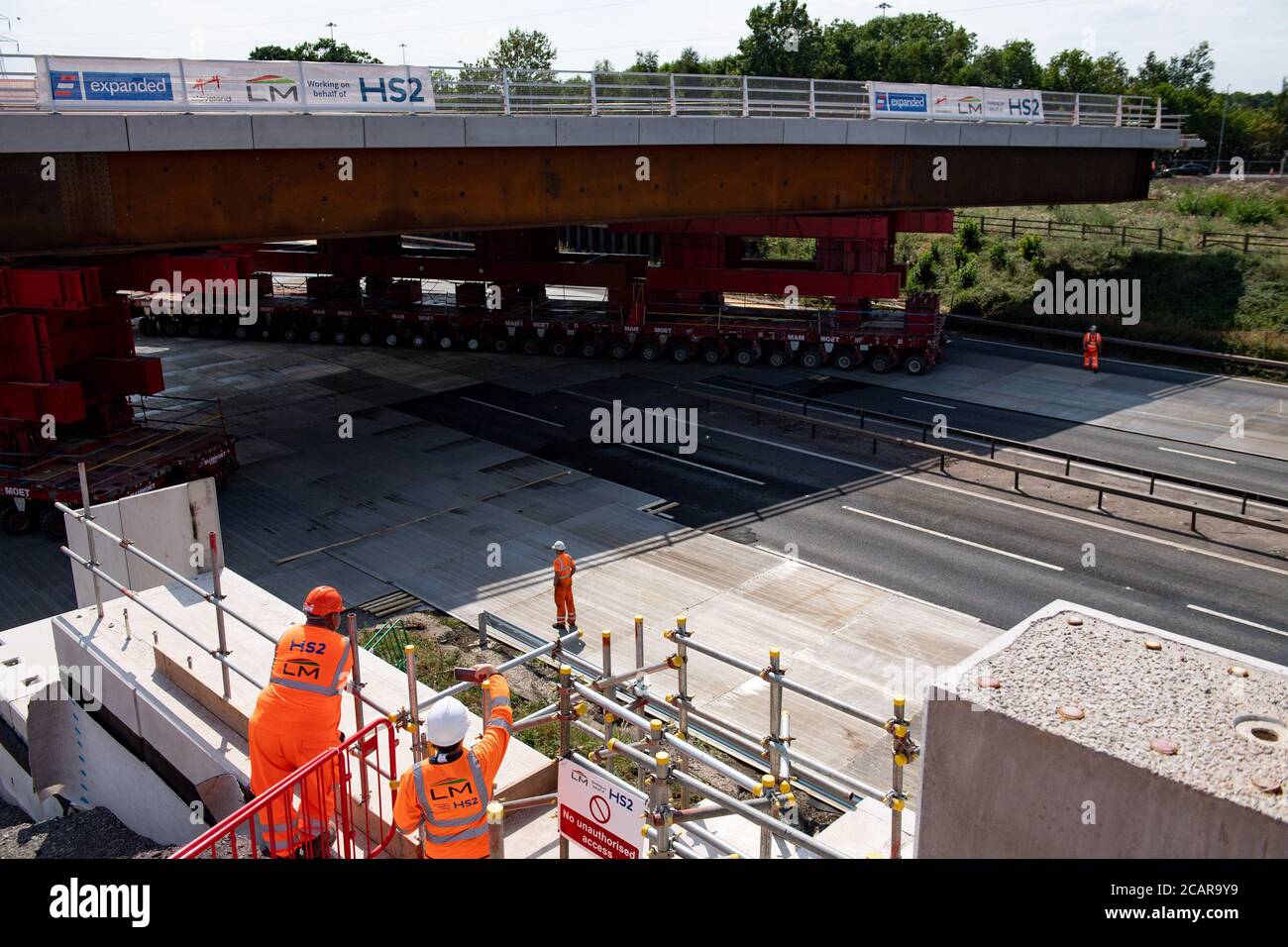HS2 workers watch as a bridge is wheeled into position over the M42 at ...