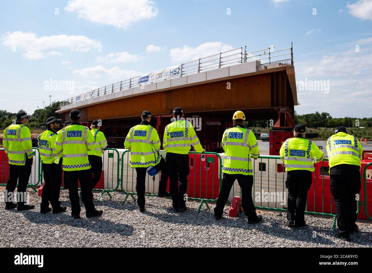 Police officers watch as a bridge is wheeled into position over the M42 ...