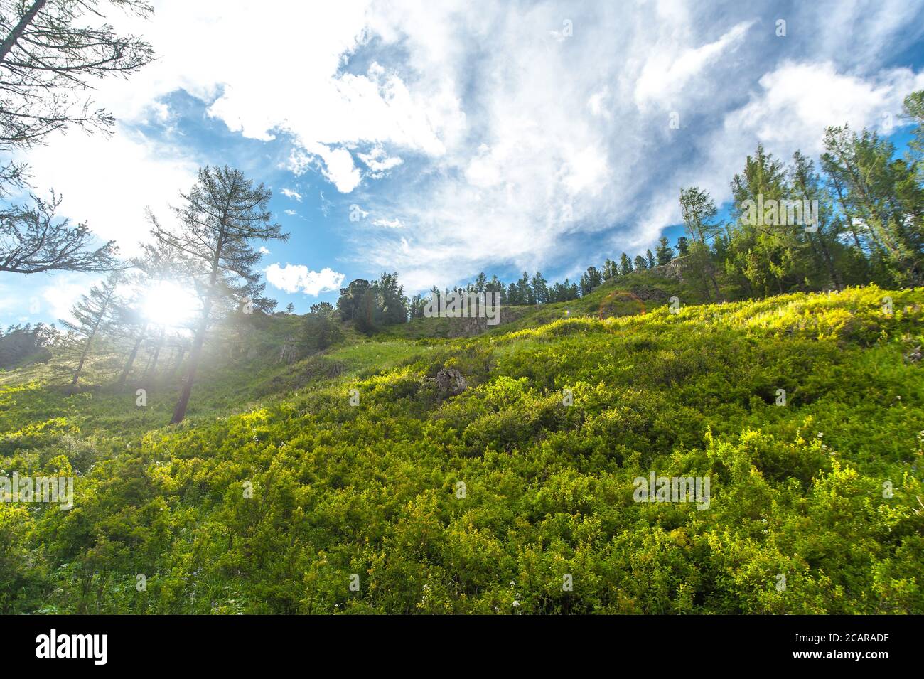 mountainous terrain and blue sky with rays of sun Stock Photo - Alamy