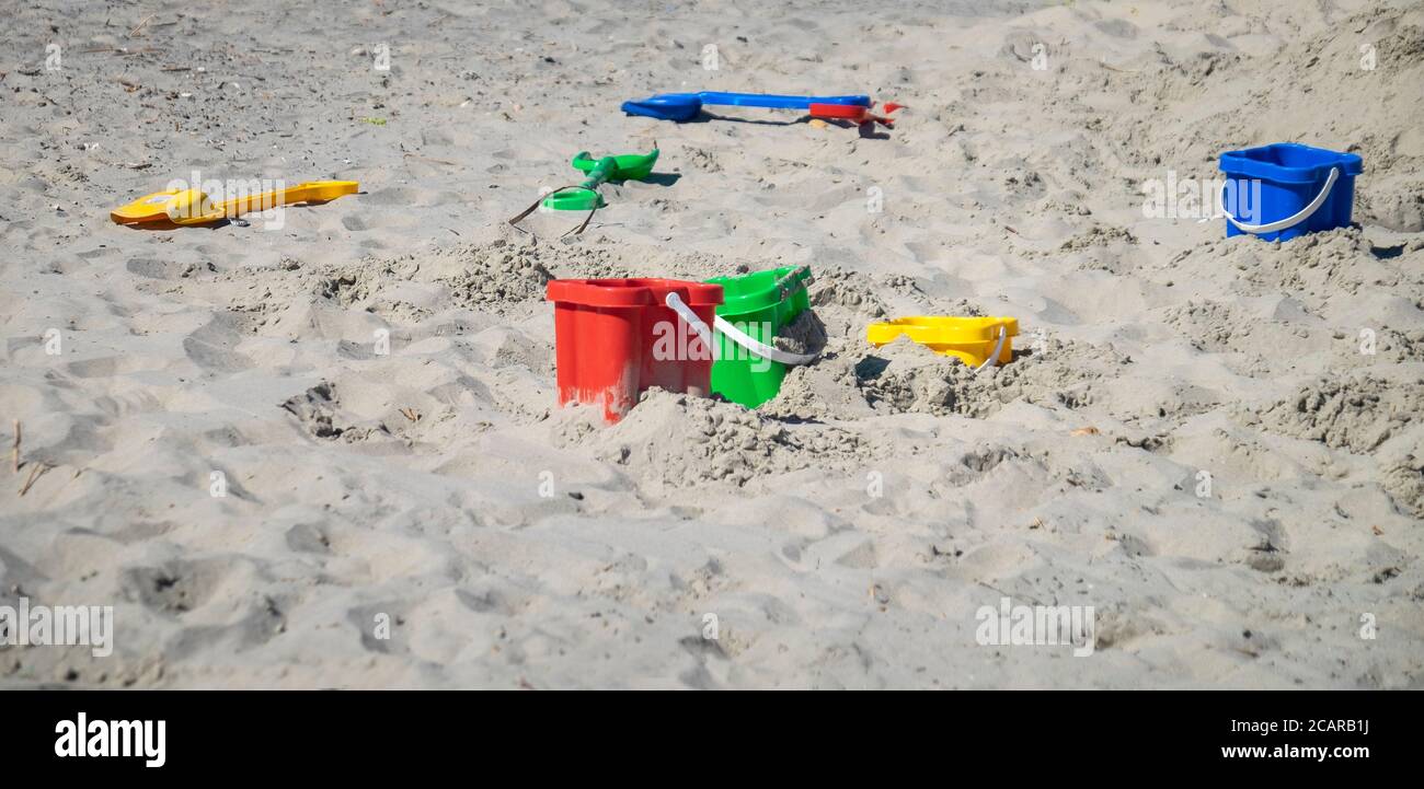 Colourful buckets and spades left laying on a sandy beach Stock Photo ...