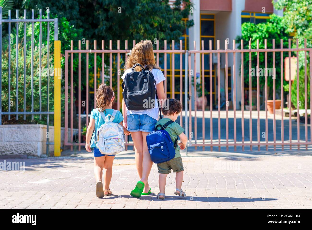 Happy school children going to school outdoor at sunny autumn day. Rear ...