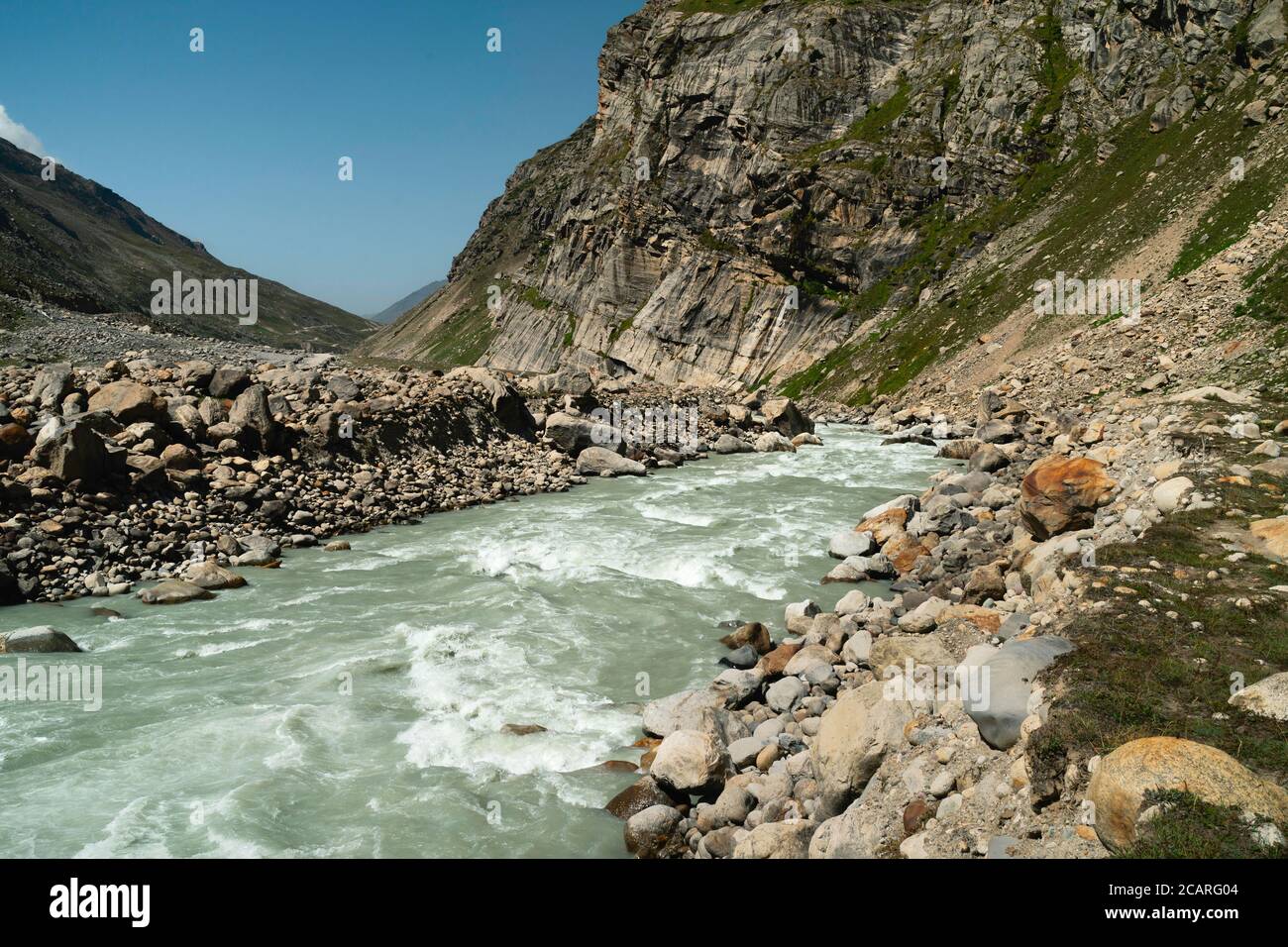 River flows through deep valley flanked by Himalayas and boulders under ...