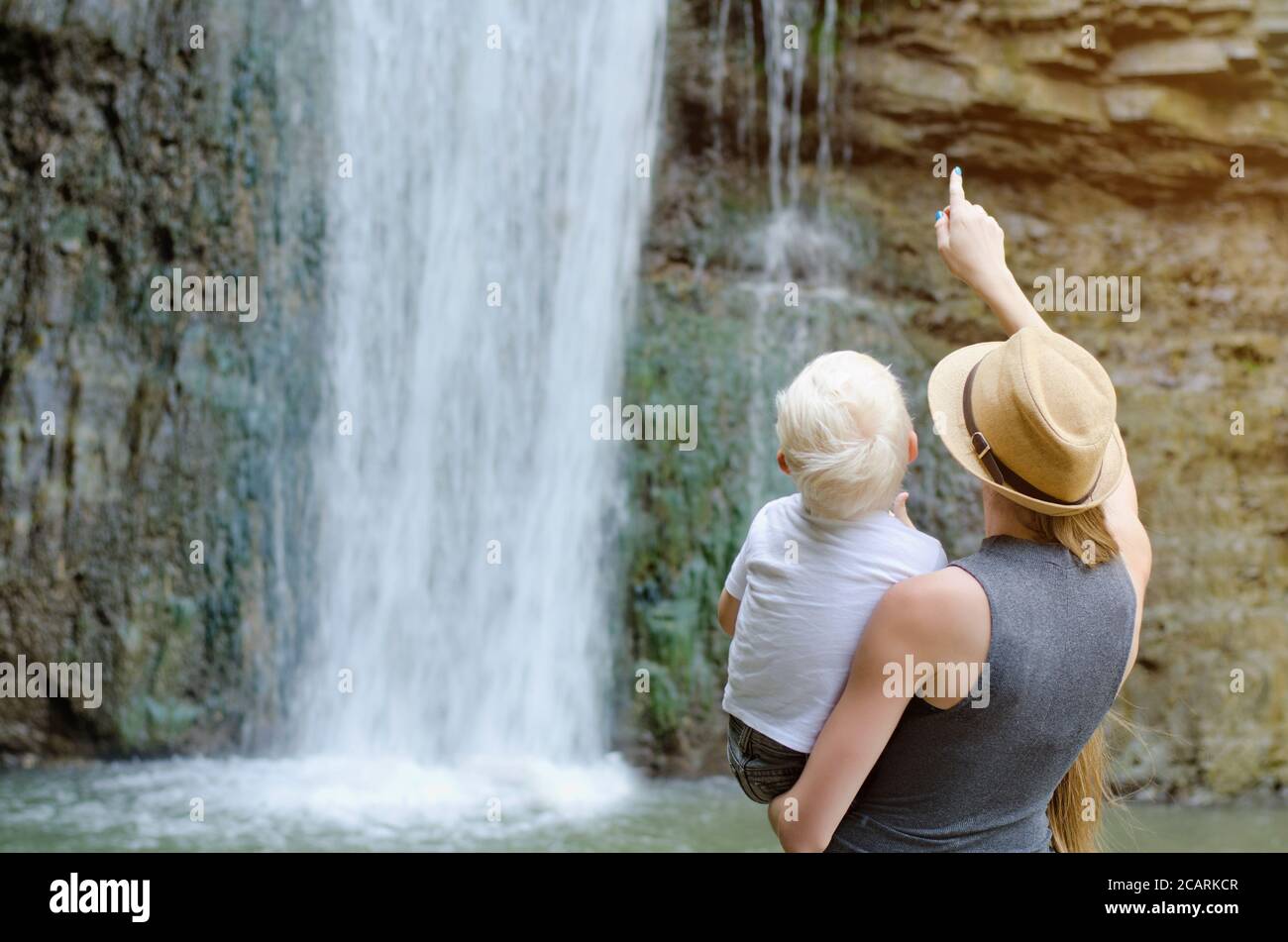 Mom and son are looking at the waterfall, the view from the back Stock ...