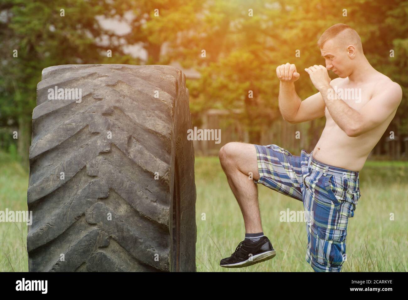 Young man boxing with the tire. Workout Stock Photo - Alamy