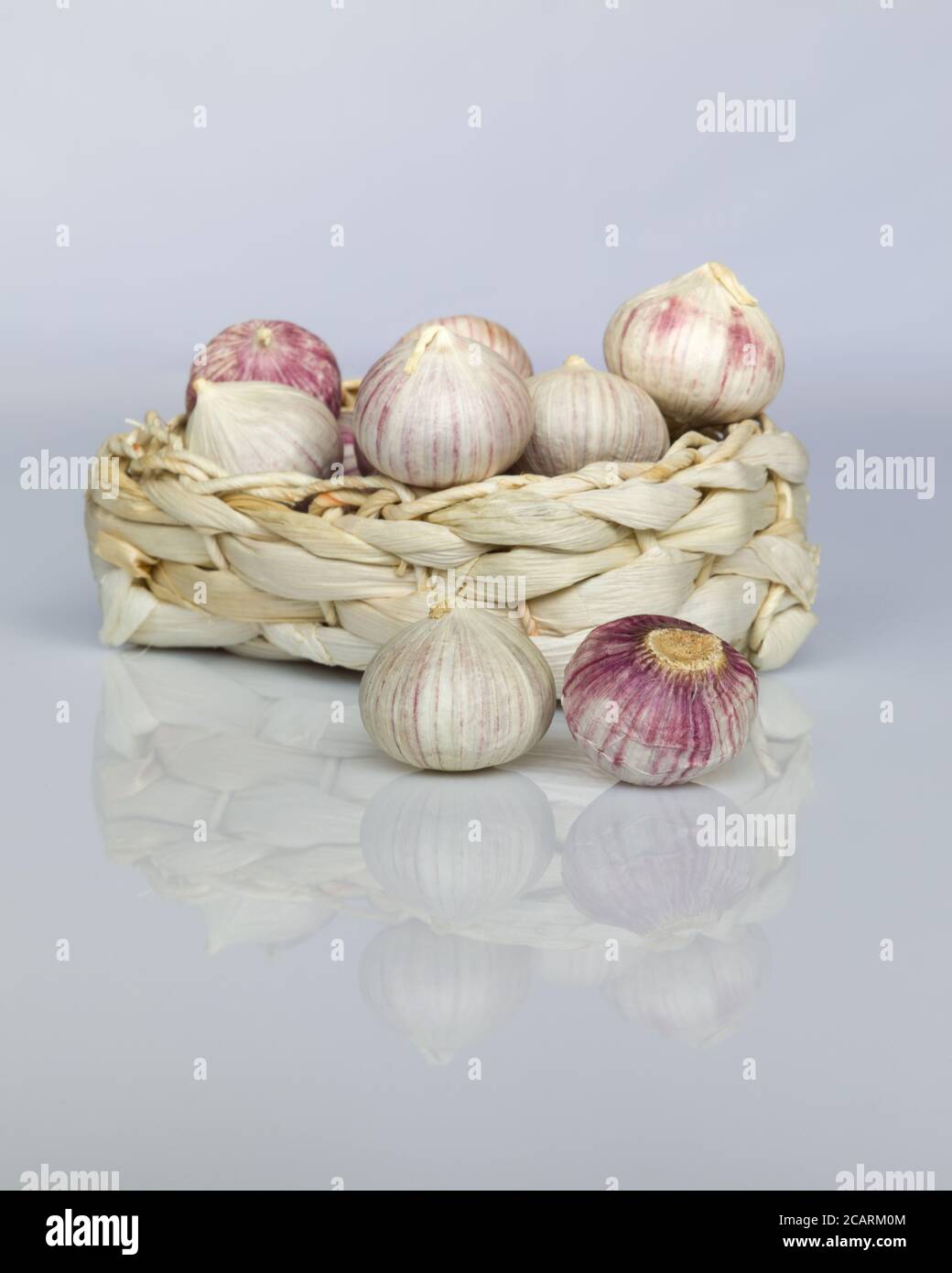 Fresh Solo garlic bulbs in a basket on a white background. They are ...