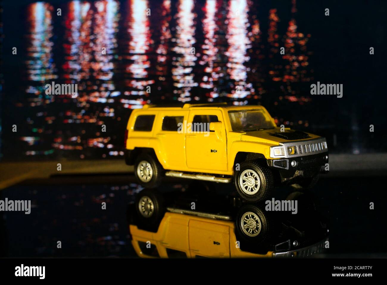 Selective focus shot of a small yellow toy car with reflection in the ...