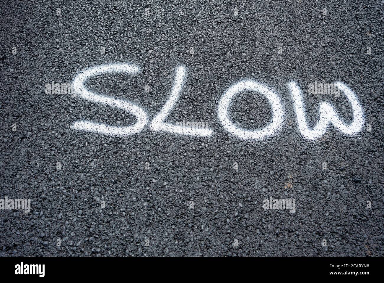 handwritten Slow sign sprayed on a road Stock Photo - Alamy