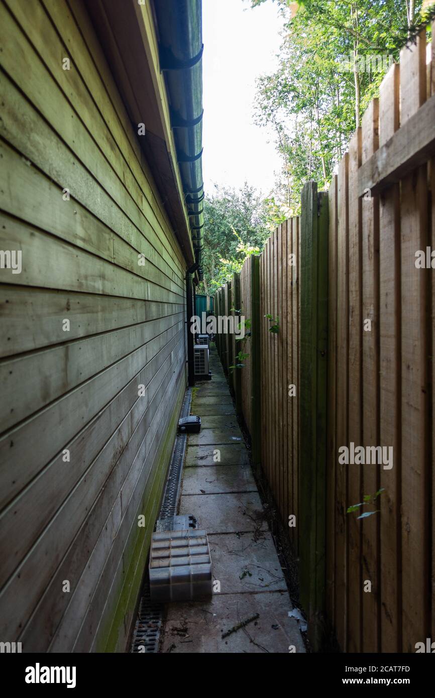 narrow dark alleyway between building and fencing Stock Photo - Alamy
