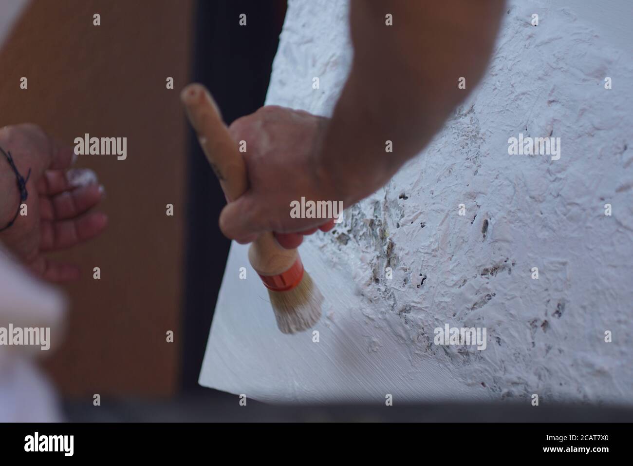 Closeup of a professional artist painting the canvas with white paint ...
