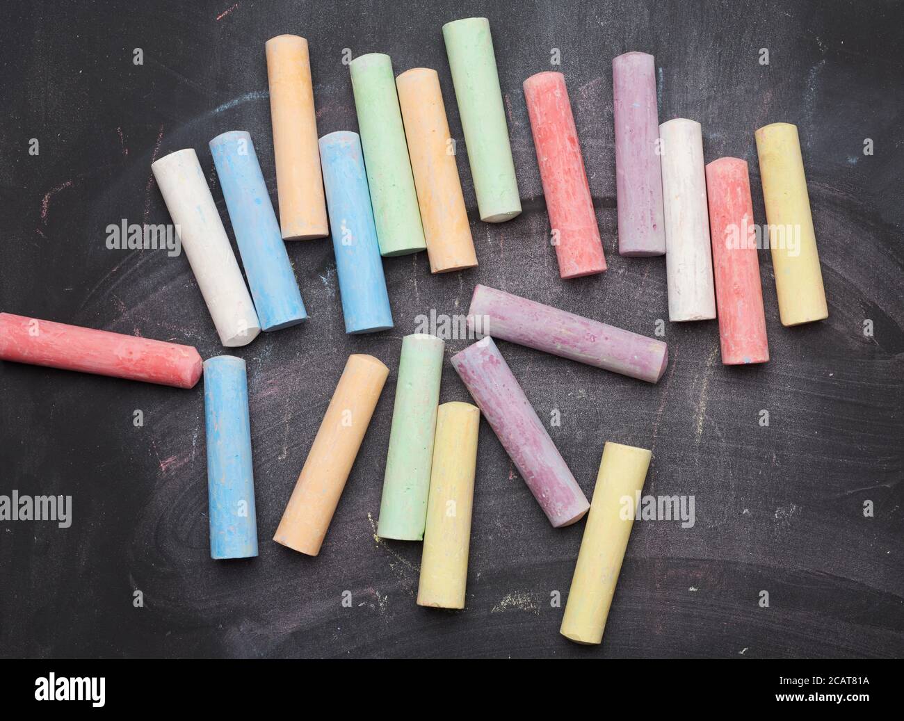 multicolored chalks on lie on empty black chalk board, top view, back ...