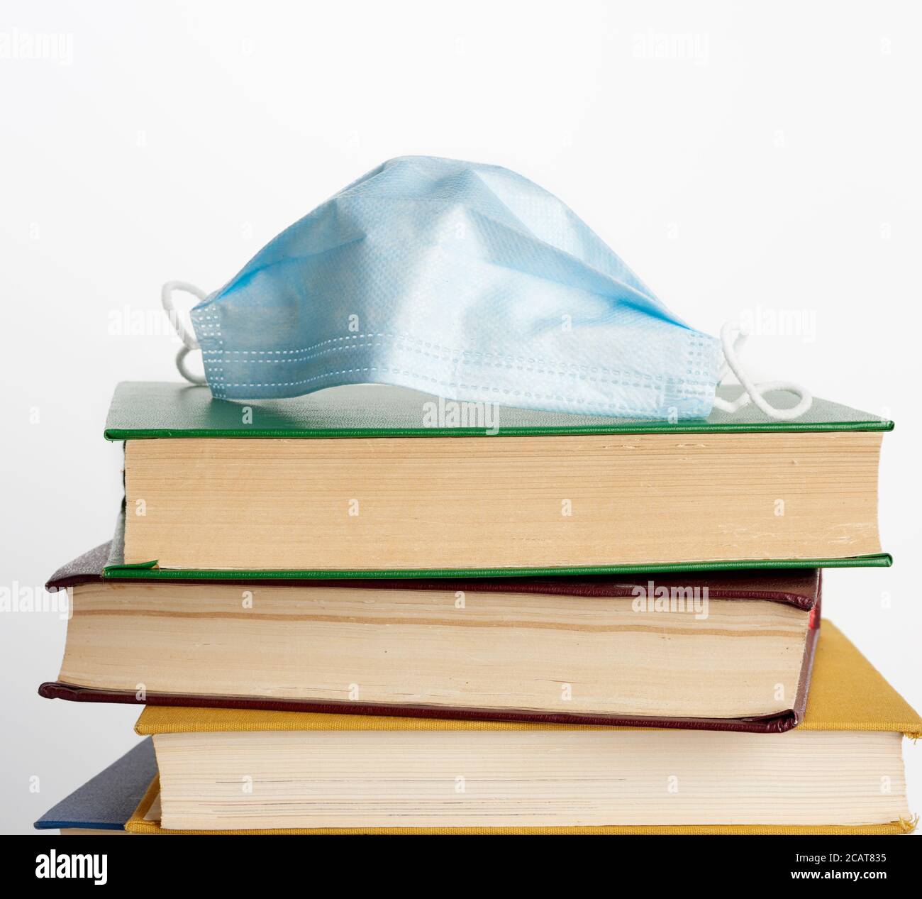 stack of various books and disposable medical masks on a white ...