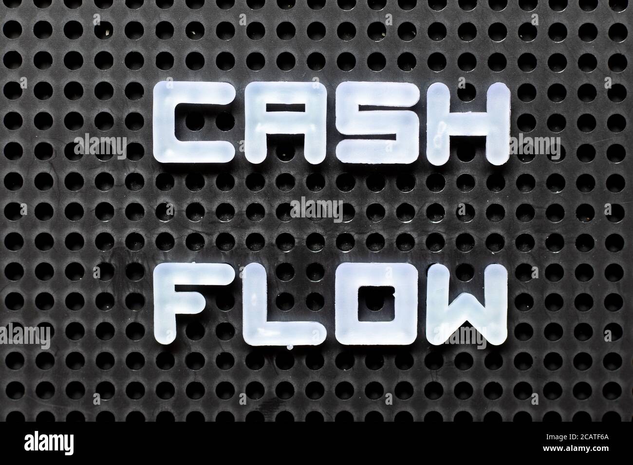 White color alphabet with word cash flow on black pegboard background ...