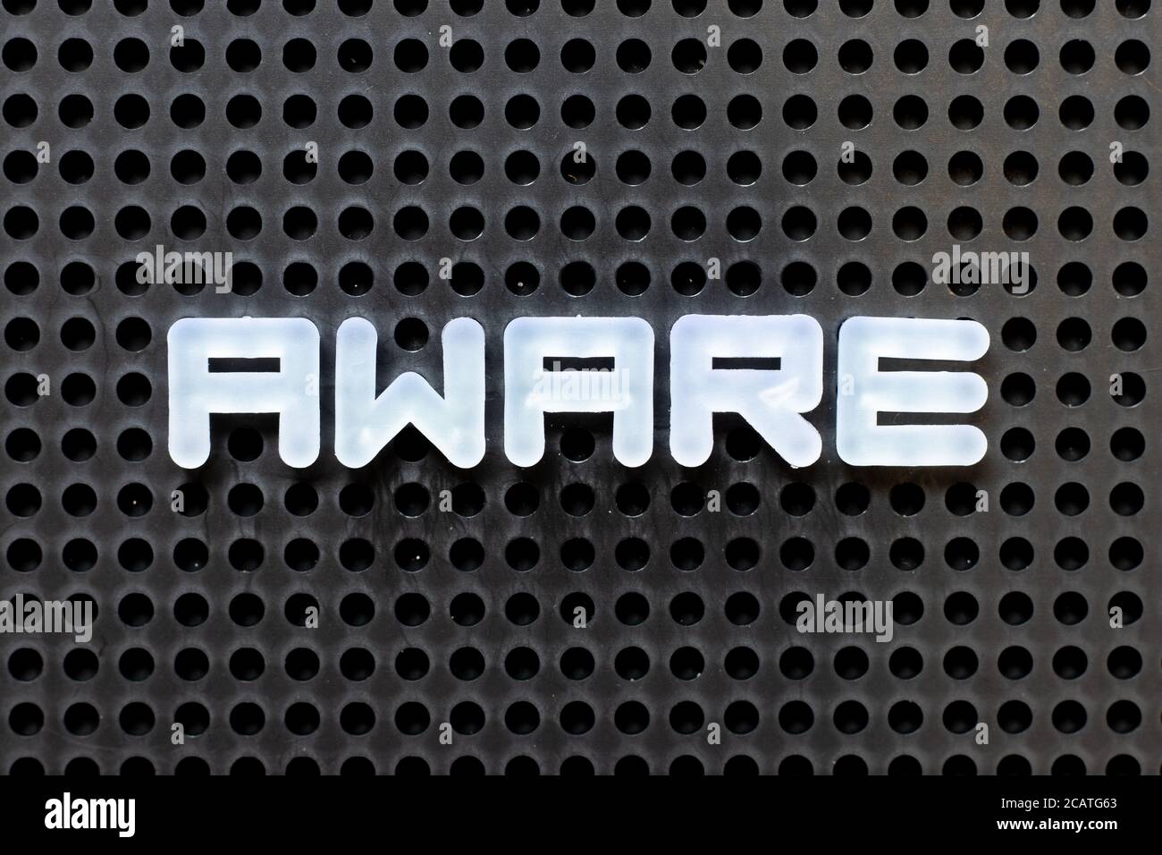 White color alphabet with word aware on black pegboard background Stock ...