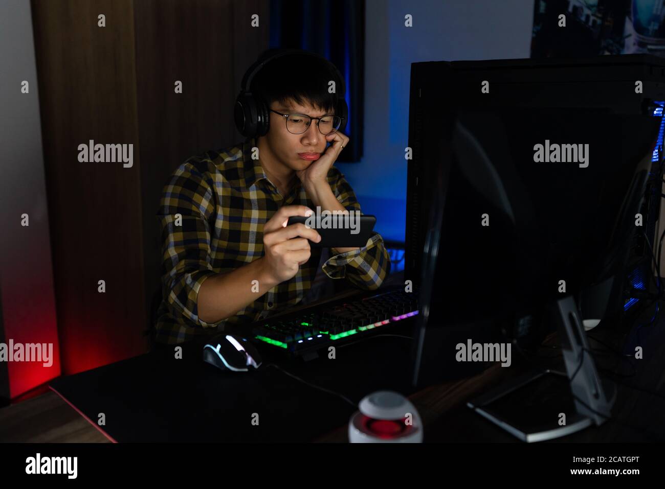 Asian man gamer in headphones stressed with hand feel depressed or ...
